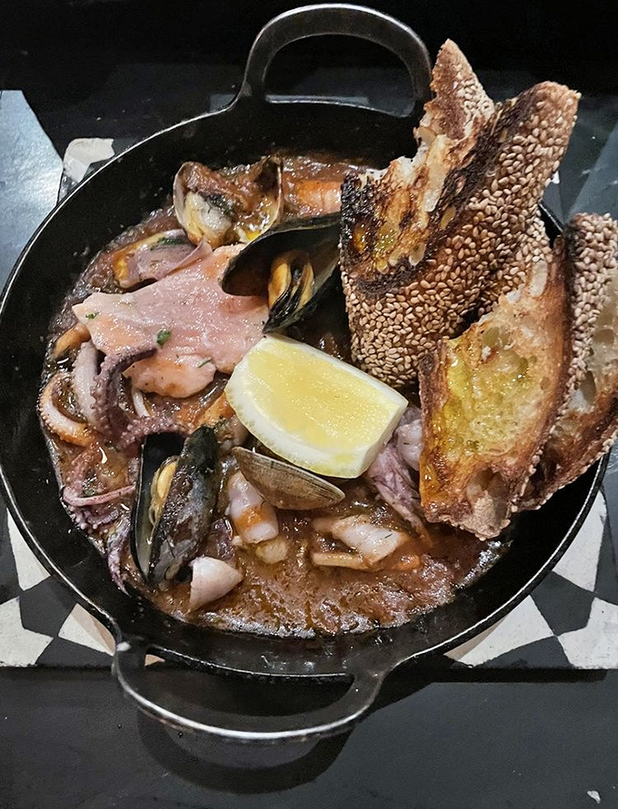 A cast-iron cauldron of seafood stew that would make Neptune himself jealous. The crusty bread stands ready for its sacred duty: sopping up every last drop.