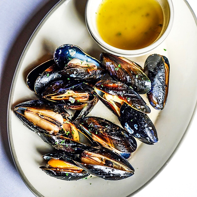 The star attraction: smoked mussels that look like they've been kissed by flavor gods, served with a buttery sauce that demands bread for dipping.