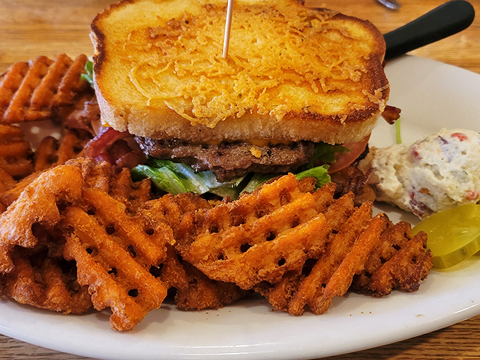 The ultimate road trip refueling station: a towering sandwich flanked by sweet potato waffle fries that could make a French chef reconsider their life choices.