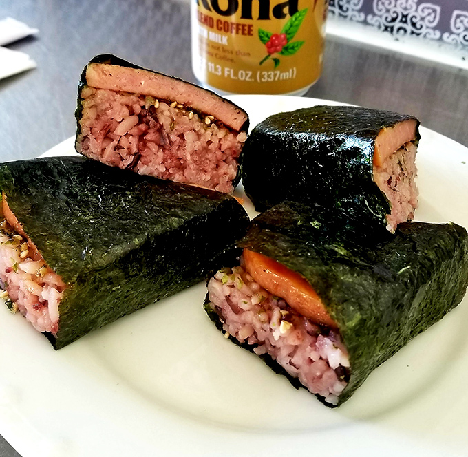 Spam musubi: Hawaii's beloved handheld delight where seaweed-wrapped purple rice cradles that iconic meat product that somehow tastes infinitely better here than from your pantry.