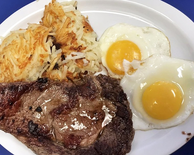 The holy trinity of diner breakfast: a perfectly seared steak, sunny-side-up eggs, and hash browns crisped to golden perfection. Morning salvation on a plate.