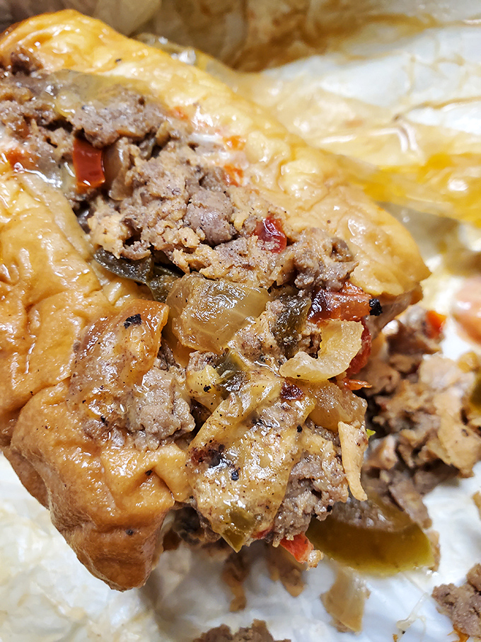 The cross-section reveals the truth &ndash; perfectly caramelized meat, melted cheese, and those sweet onions nestled in a roll that's both sturdy and yielding.