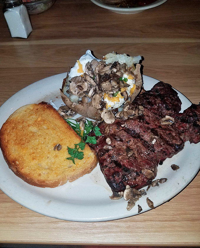 This steak and loaded baked potato plate isn't just dinner&mdash;it's therapy on a white ceramic plate. The mushroom garnish is just showing off.
