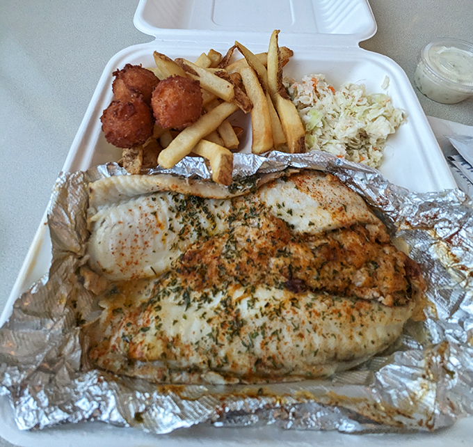 The stuffed flounder arrives like royalty on its foil throne, accompanied by its loyal subjects: hush puppies, fries, and coleslaw.