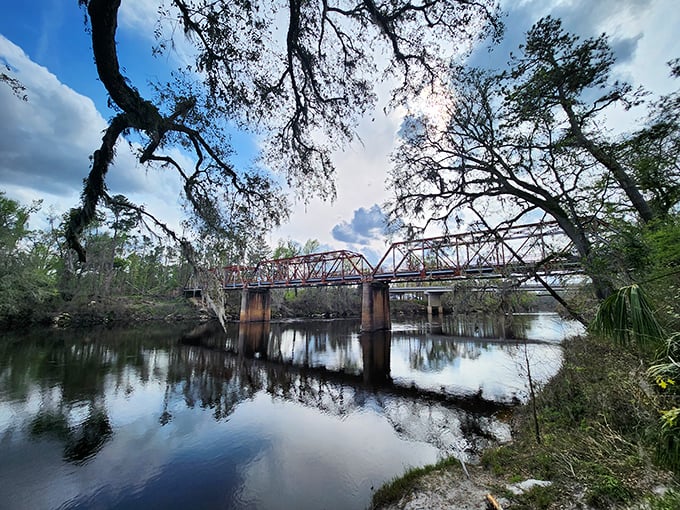 The Suwannee Springs Bridge reflects perfectly in the water below, creating the optical illusion of a complete metal circle—a portal to the past.