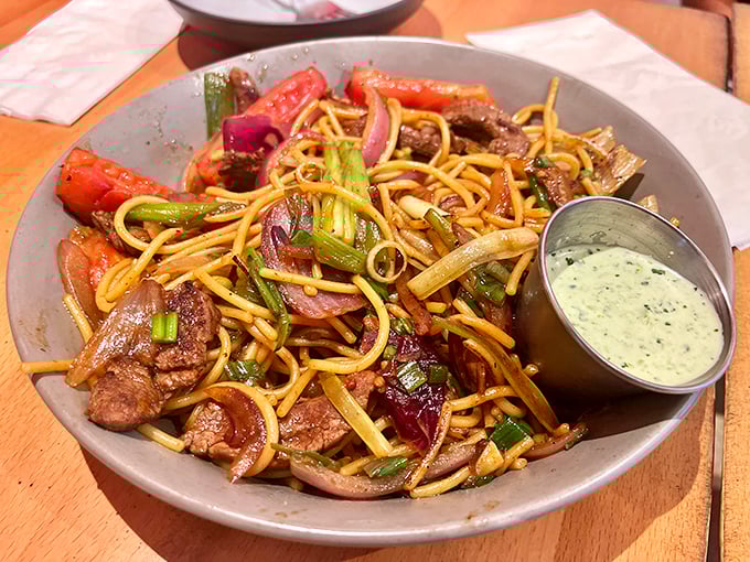 Tallarin Saltado brings Peru to your plate with tender beef, vibrant vegetables, and noodles that have absorbed all the right flavors. That green sauce? Liquid gold.