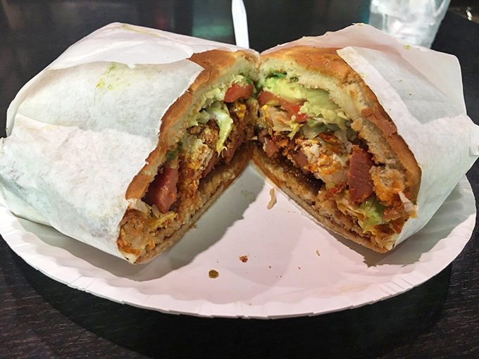 The Torta Cubana reveals its glorious layers—a cross-section of culinary genius with avocado, meat, and veggies in perfect harmony.