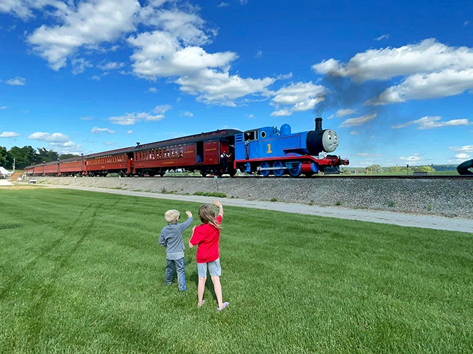 Two young admirers wave to Thomas the Tank Engine, their excitement as palpable as the steam billowing from his iconic blue frame.