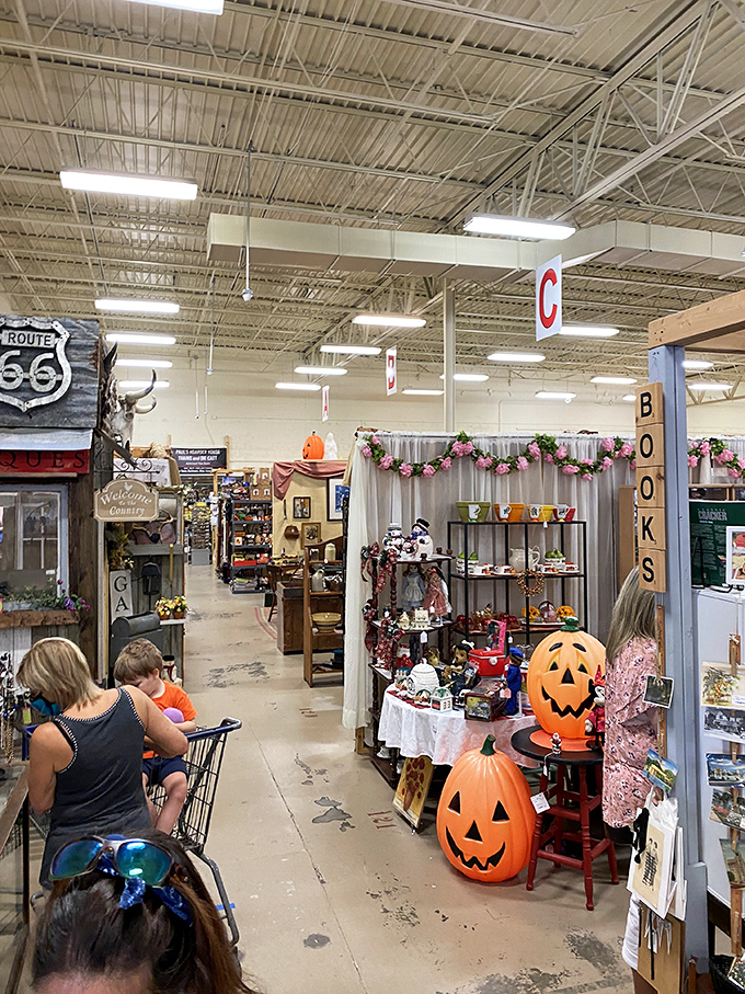 Wide aisles lead to vendor booths where Halloween decorations signal seasonal treasures. Every aisle promises a different decade's worth of discoveries.