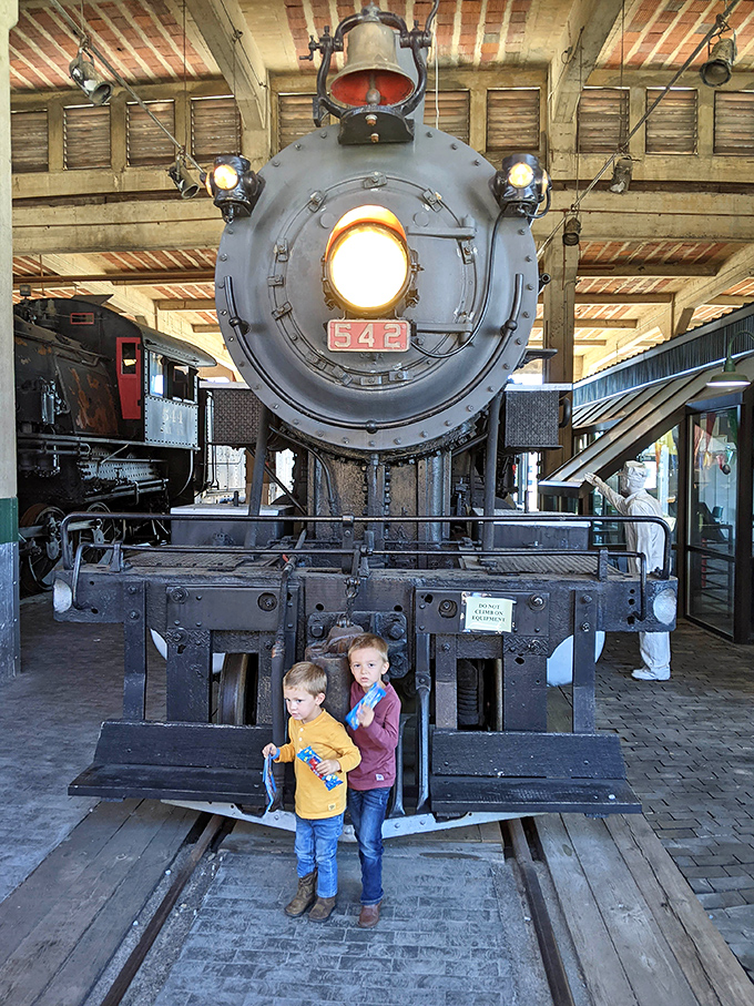 Two young train enthusiasts stand dwarfed by locomotive 542's massive front end, their expressions capturing the childlike wonder we all feel around these iron giants.