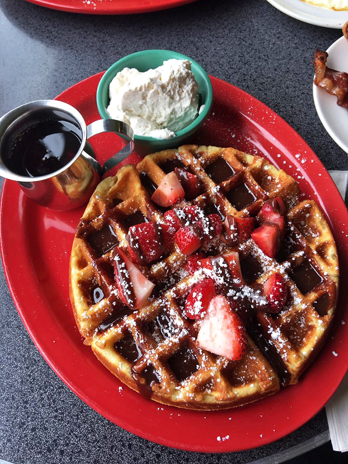 This waffle doesn't need a resume—it speaks for itself with those perfect grid marks, fresh strawberries, and a dollop of cream that's basically showing off.