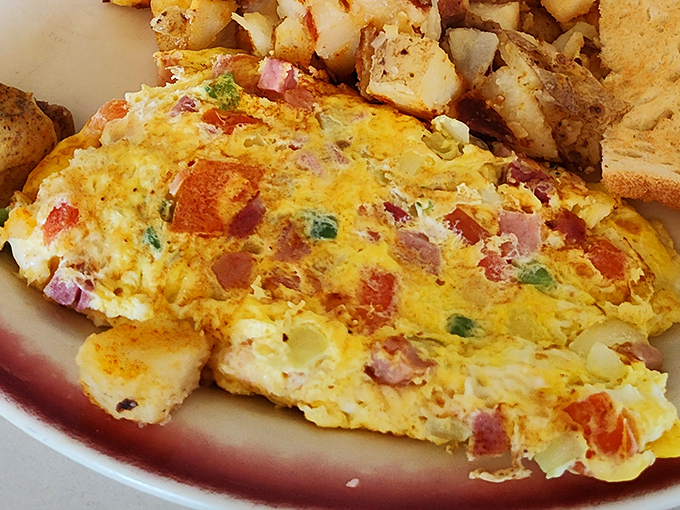 This Western omelet contains more colorful characters than a small-town parade, all wrapped in a fluffy yellow blanket of perfectly cooked eggs.