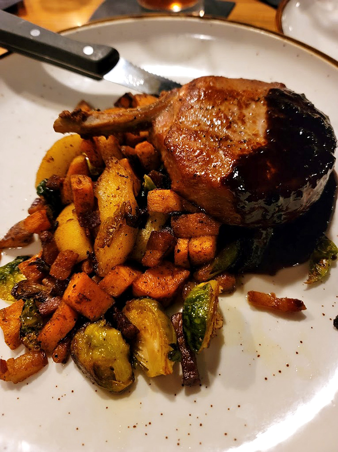 The pork chop that launched a thousand road trips, surrounded by a colorful medley of roasted vegetables that steal glances.