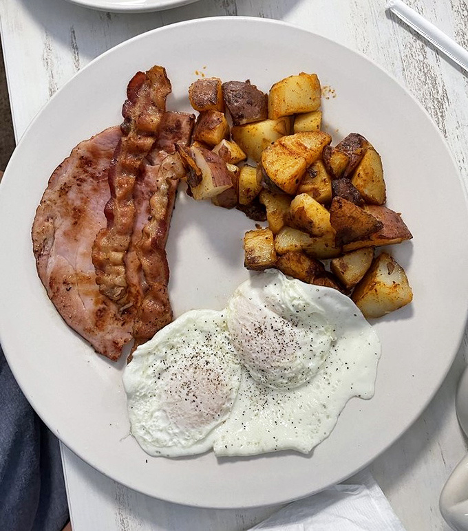 Breakfast harmony achieved: crispy bacon, sunny eggs, and home fries that could make a potato farmer weep with pride.
