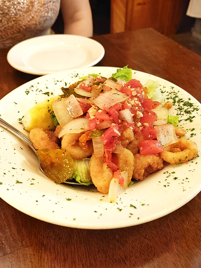 Crispy calamari topped with fresh tomato and onion&mdash;proof that sometimes the best things in life come in crispy, golden packages with a squeeze of lemon.