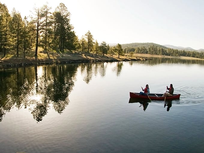 Serenity now! Two paddlers glide across mirror-like waters while the pines stand sentinel. Noise cancellation courtesy of Mother Nature herself.