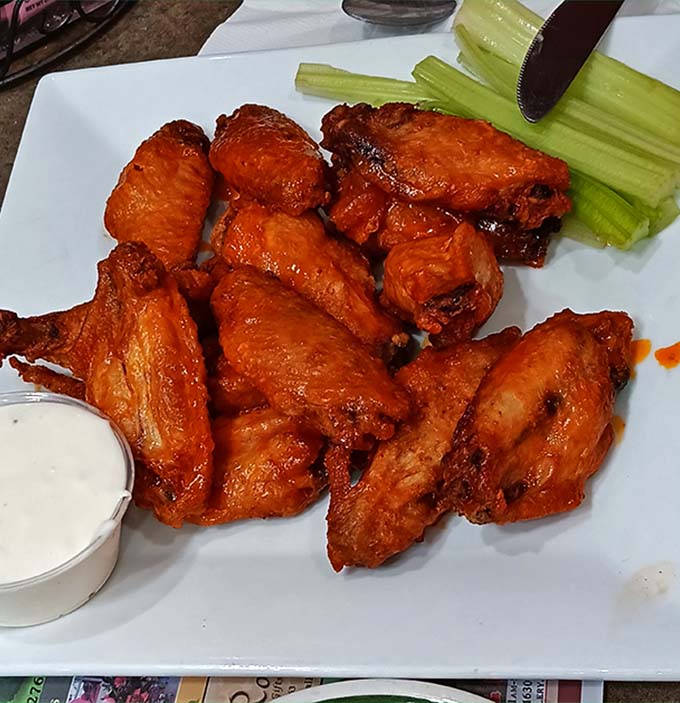 Buffalo wings glistening like edible garnets, accompanied by celery sticks that know they're just moral support for the main event.