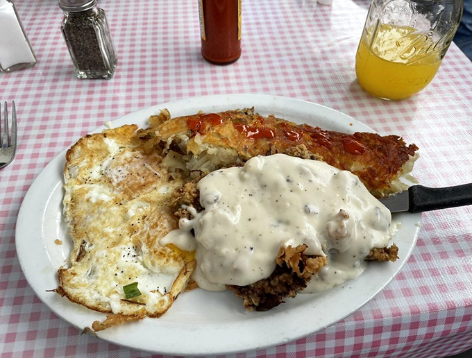 Country gravy cascading over chicken fried steak like a delicious waterfall, with sunny-side eggs standing guard &ndash; comfort food that means business.