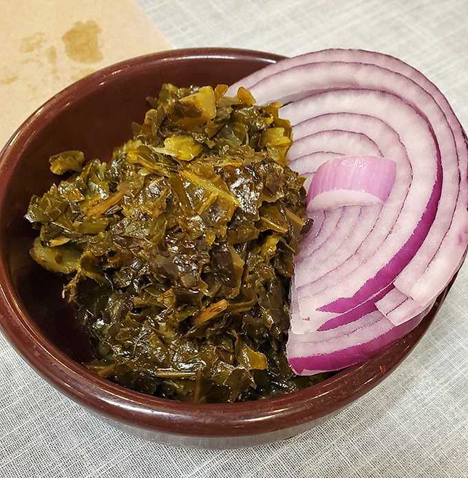 These collard greens have clearly been simmering since breakfast, paired with red onion slices that add just the right bite of freshness.