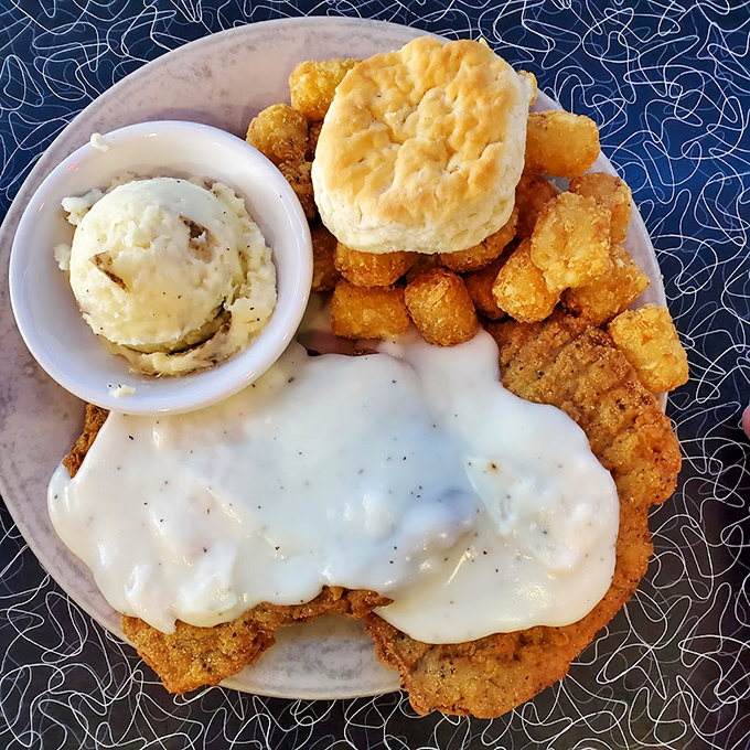 Country fried steak smothered in gravy with a golden biscuit standing by. Southern comfort food that's achieved liftoff to perfection.