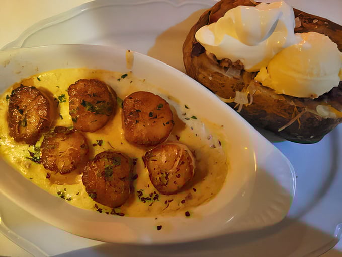 These golden-seared scallops swimming in butter sauce aren't just seafood&mdash;they're little ocean medallions of happiness served alongside a potato that's dressed better than most people.