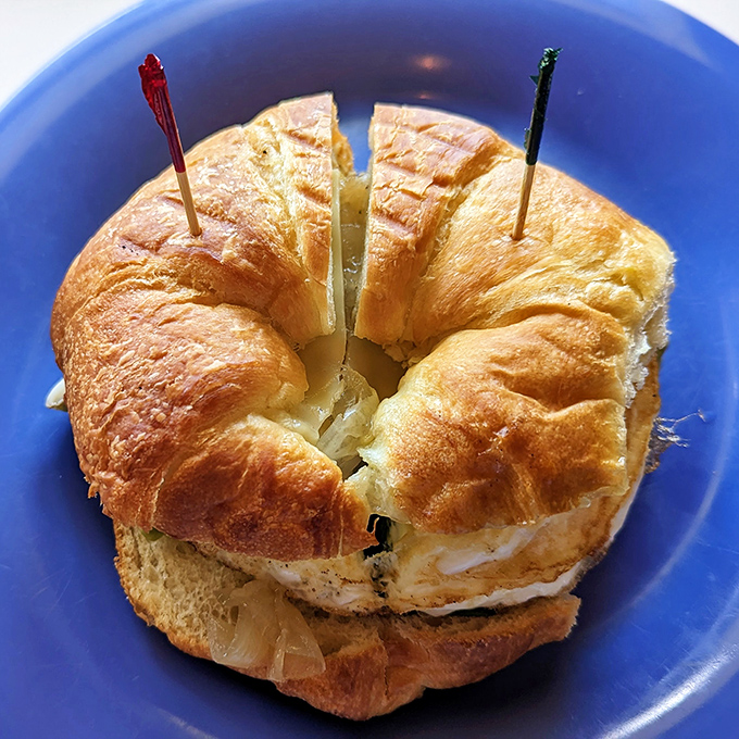 Croissant architecture at its finest. This golden, flaky sandwich held together with colorful toothpicks is breakfast engineering that works.
