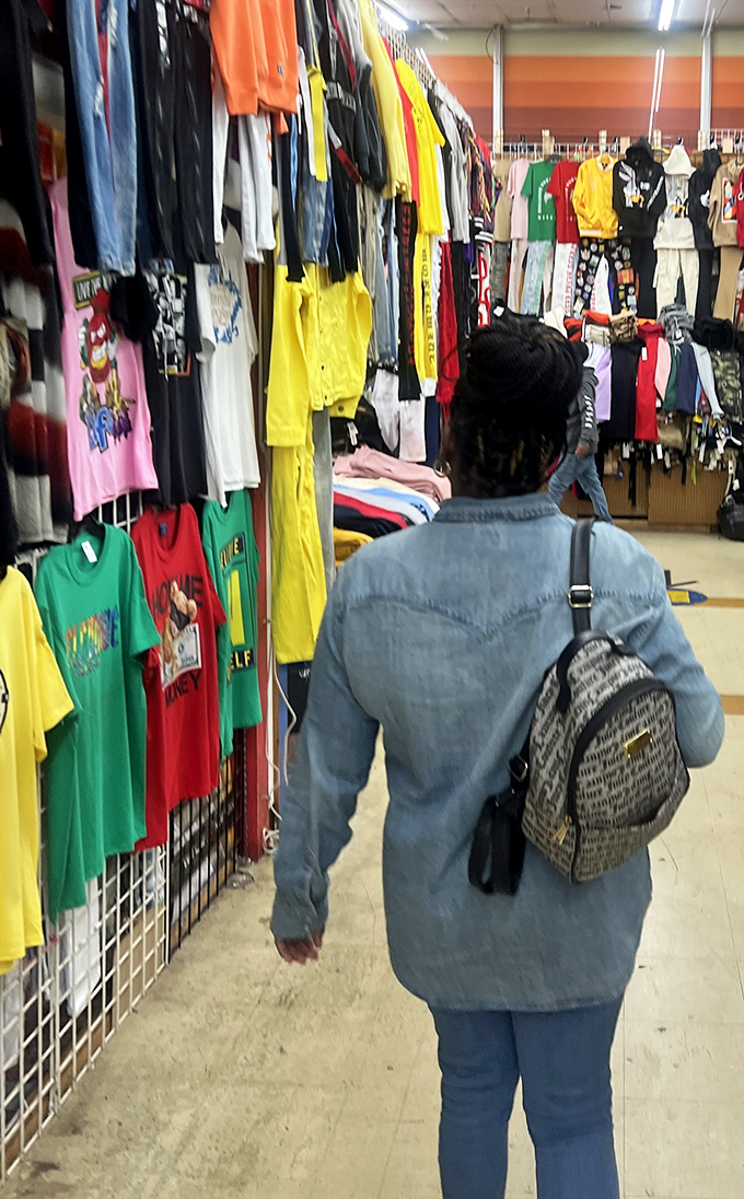 A shopper navigates the clothing jungle, where vibrant t-shirts compete for attention like contestants on a particularly loud game show.