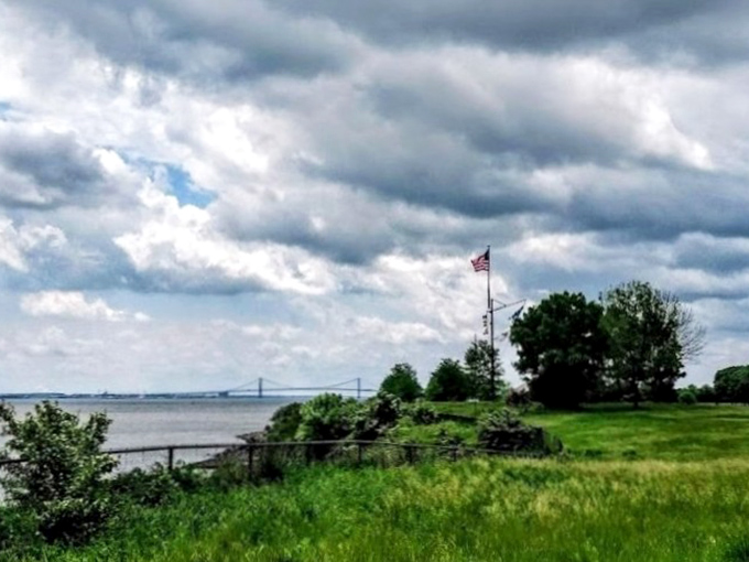 An American flag stands sentinel over the river vista. Some patriotic displays don't need parades&mdash;just wind, water, and open sky.