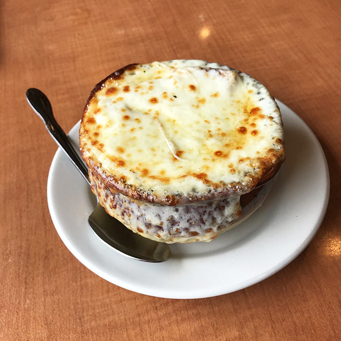 This French onion soup isn't just topped with cheese—it's wearing a magnificent crown that would make any royal family jealous.