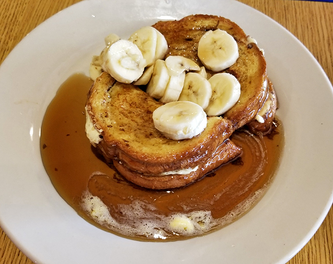 French toast that's achieved celebrity status, crowned with fresh banana slices and swimming in maple syrup. This isn't breakfast&mdash;it's dessert with permission.