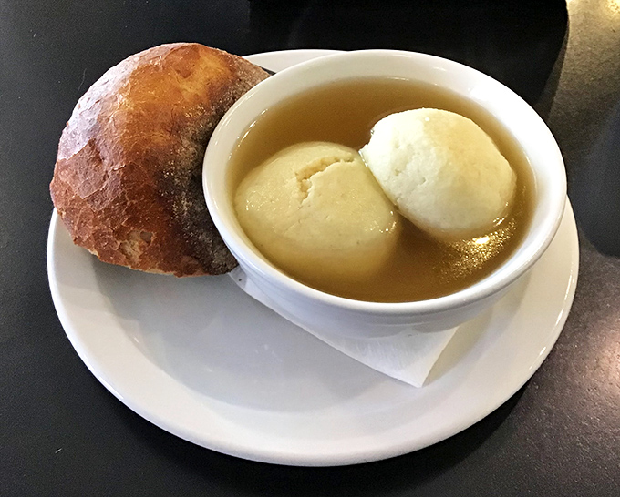 Matzo ball soup that would make your grandmother nod in approval&mdash;golden broth cradling fluffy dumplings like clouds in a warm, savory sky.
