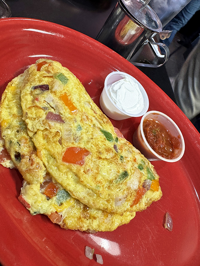 This isn't just an omelet; it's a technicolor dream of perfectly folded eggs embracing peppers, ham, and cheese. The side of salsa adds just the right kick.