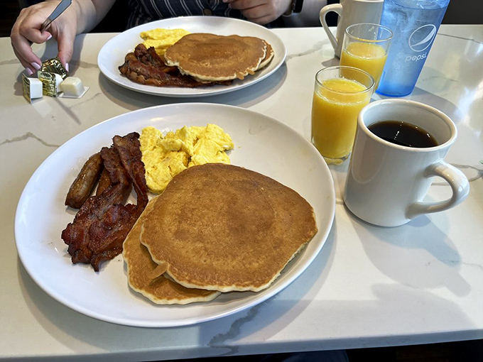 The holy trinity of breakfast perfection: golden pancakes, scrambled eggs, and bacon that's achieved that magical balance between crispy and chewy.