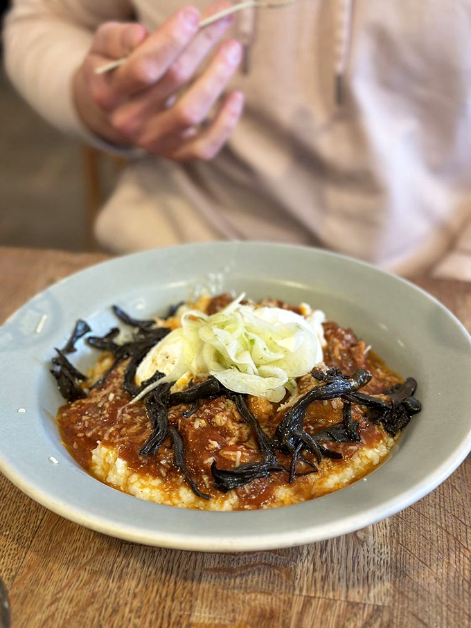 Not your grandfather's grits! This soulful bowl transforms humble ingredients into something worthy of worship, with those black strips adding umami depth that would make a monk break their silence.