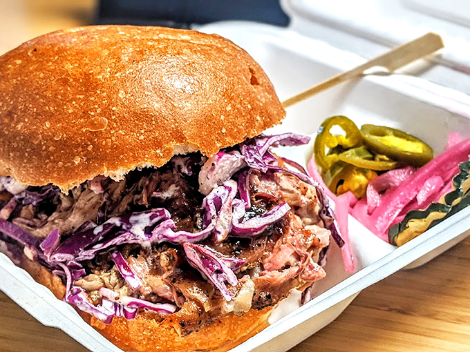 Not just a pulled pork sandwich, but a textural symphony. The purple slaw and pickled vegetables provide the perfect counterpoint to that smoky, tender meat.