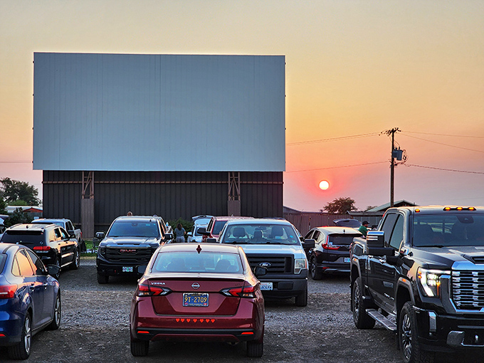 Cars line up like eager moviegoers, their headlights dimmed in anticipation as the sun takes its final bow on the horizon.