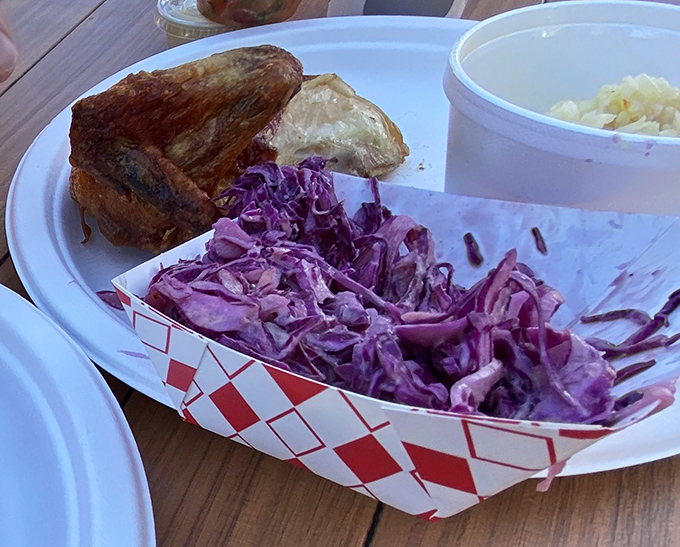 Purple cabbage slaw that's dressed to impress, sitting alongside what appears to be roasted chicken. Cole slaw that actually deserves a place at the table.