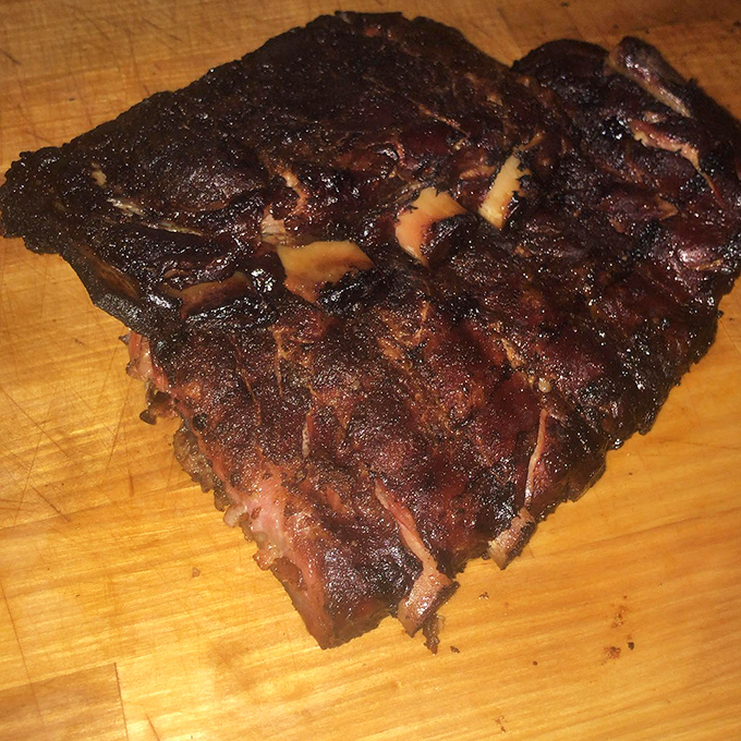 These ribs have the kind of gorgeous char that makes vegetarians question their life choices. Carnivore poetry on a wooden cutting board.