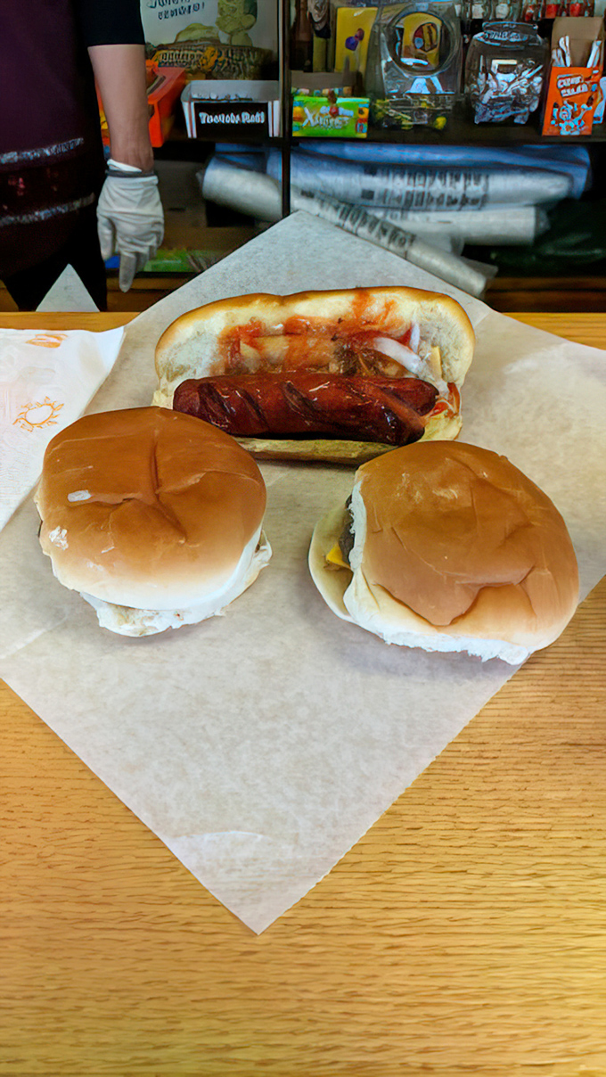 The perfect trio &ndash; two sliders and a hot dog, arranged on parchment like a still life painting that's about to become a delicious memory.