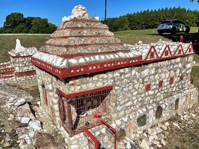 A stone pyramid rises among its neighbors like a miniature ancient wonder. The red-trimmed cage suggests this might be the local zoo for imaginary micro-elephants. 