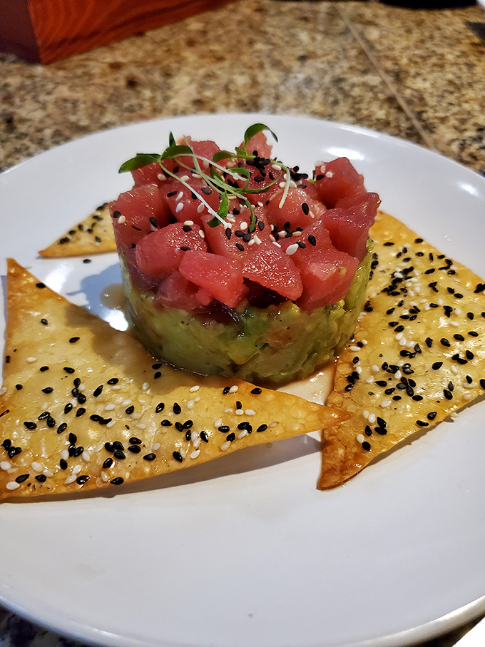 Tuna tartare artfully presented with avocado and crispy accompaniments that would make any sushi chef proud.