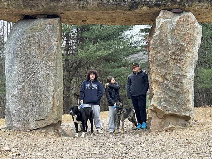 The megalithic doorway frames visitors and their four-legged companions perfectly. Even the dogs seem to sense they've crossed into somewhere special.