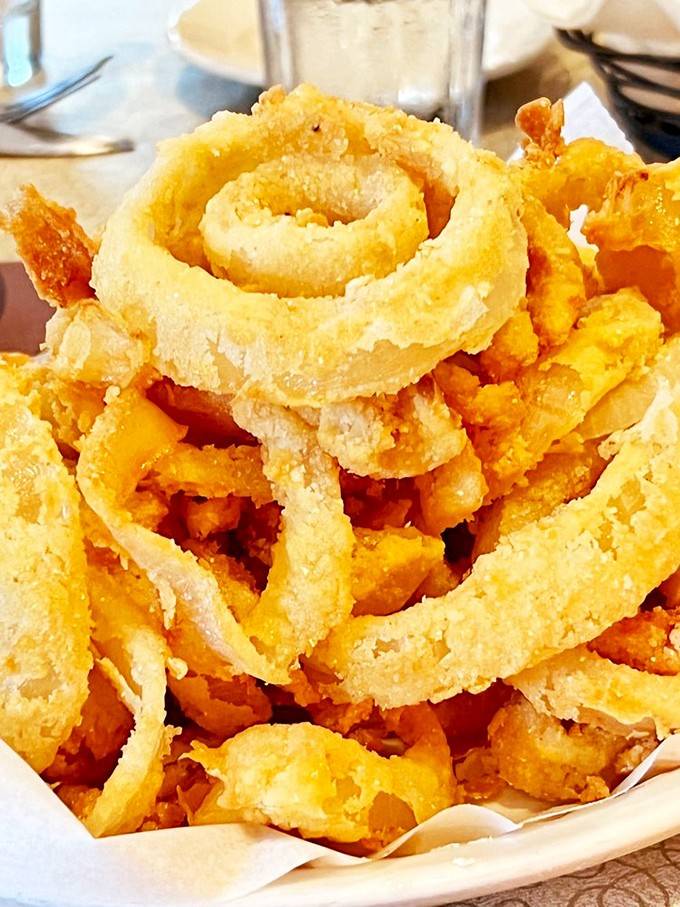 Golden onion rings that tower like edible skyscrapers, crispy enough to hear the crunch from across the room.