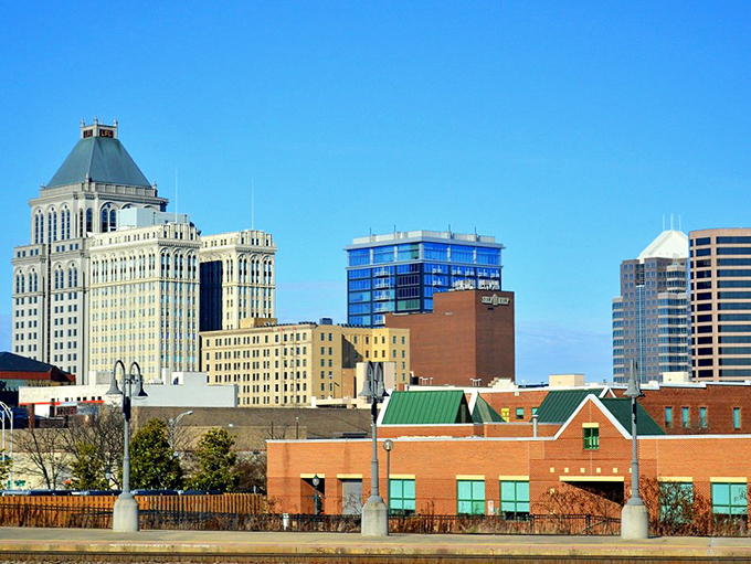 Look up and admire the striking skyline of Greensboro, where classic architecture meets modern glass under a beautiful blue sky.