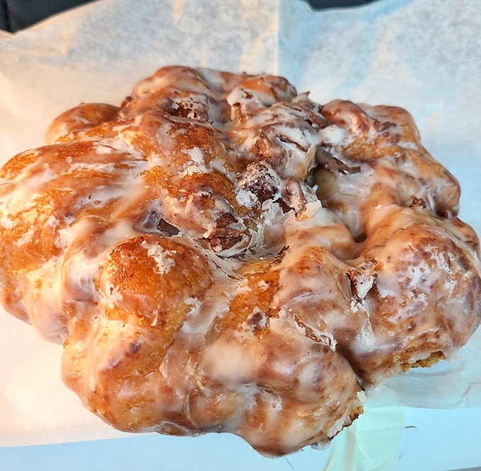 The apple fritter&mdash;that magnificent, irregular rebel of the donut world&mdash;glistening with glaze and refusing to conform to circular expectations.