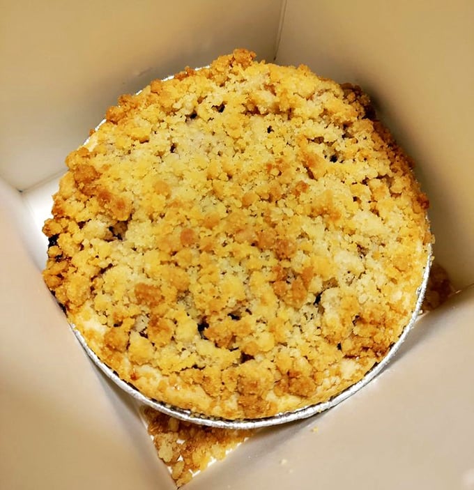 Golden apple pie with crumb topping that whispers sweet promises of childhood comfort and cinnamon dreams.