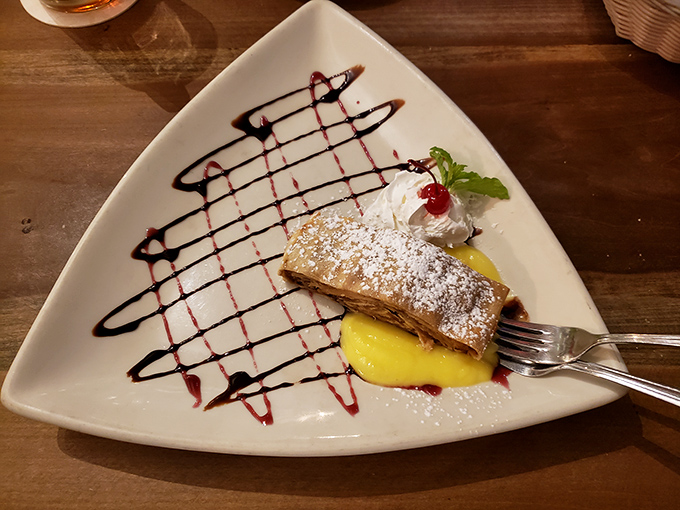 Apple strudel that deserves its own passport. Flaky pastry, warm apples, and that artistic drizzle of sauce&mdash;dessert diplomacy at its finest.