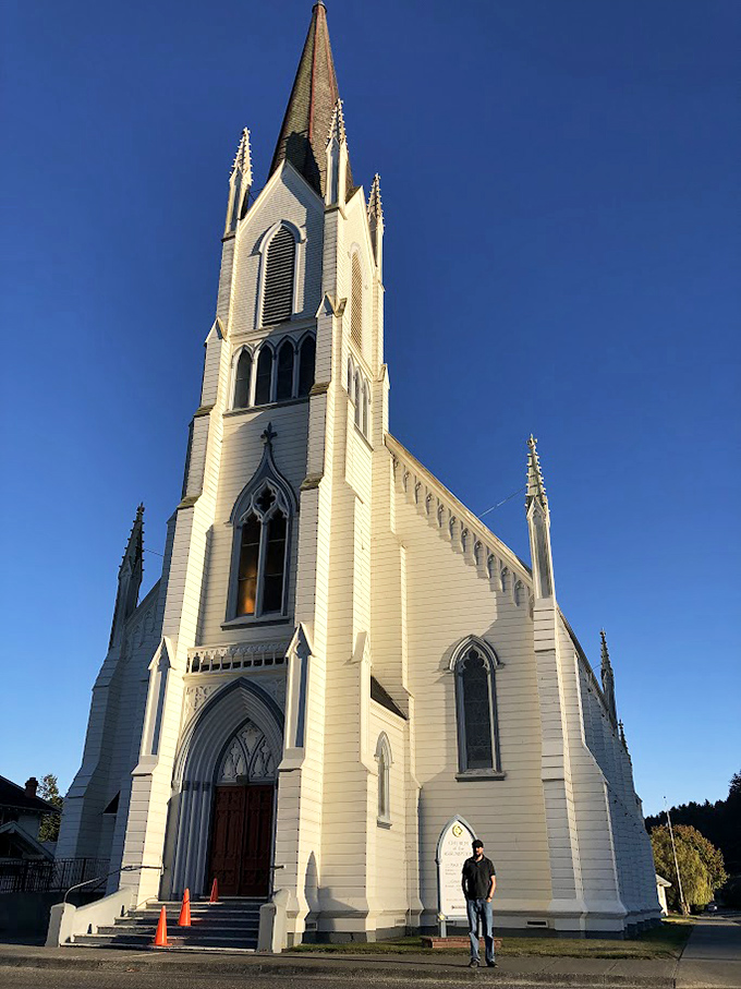 Assumption Catholic Church reaches skyward with Gothic splendor, its white wooden frame a beacon of faith against Ferndale's blue skies.