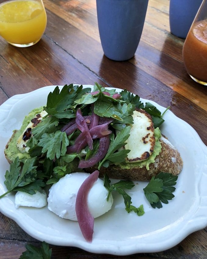 Avocado toast that makes millennials' dreams come true, with poached eggs standing by like loyal bodyguards protecting green gold.