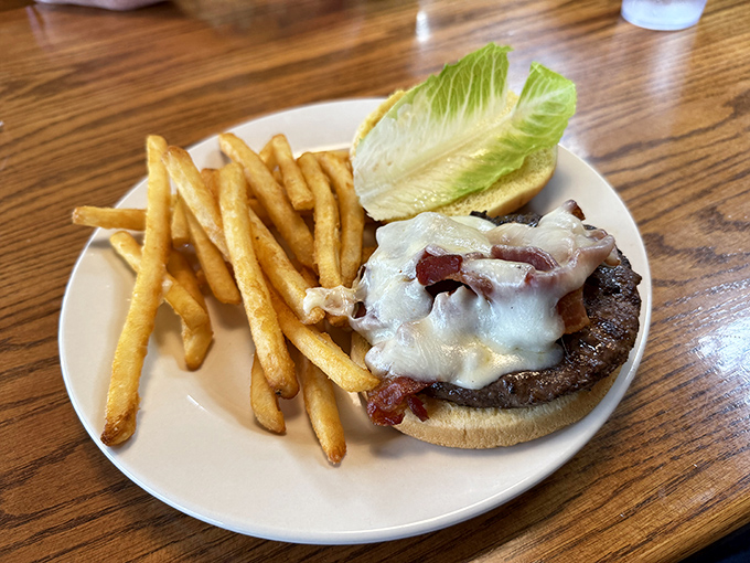This isn't just a burger&mdash;it's architecture. Melted cheese cascades over bacon and beef like a dairy waterfall, with golden fries standing at attention nearby.